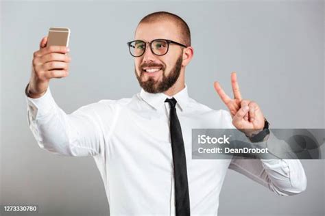 스마트 폰에서 셀카를 찍는 동안 안경과 넥타이에 성공적인 성숙한 남자 회색 배경에 고립 감독에 대한 스톡 사진 및 기타 이미지