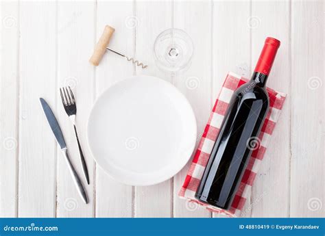 Table Setting With Empty Plate Wine Glass And Red Wine Bottle Stock