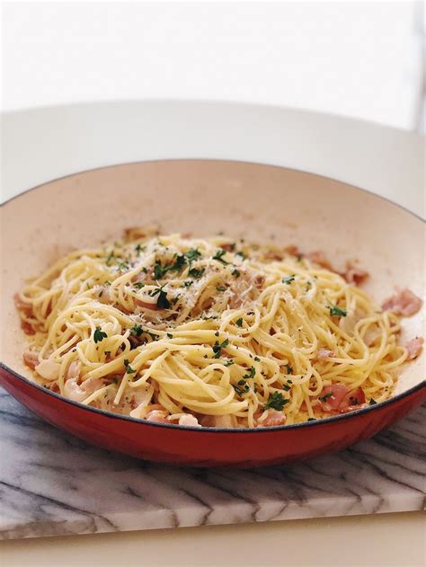 A Red Bowl Filled With Pasta On Top Of A Marble Counter