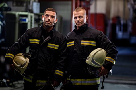 포즈를 취하는 두 명의 전문 소방관 제복과 보호 헬멧을 착용한 소방관 배경에 소방차 서 있기에 대한 스톡 사진 및 기타 이미지 서 있기 소방관 2명 Istock