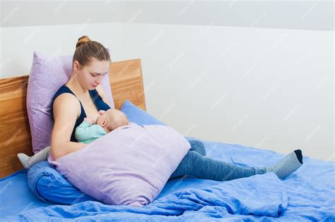 Mãe Relaxada Amamentando Bebê Sentado Na Cama Em Um Quarto Cercado Por