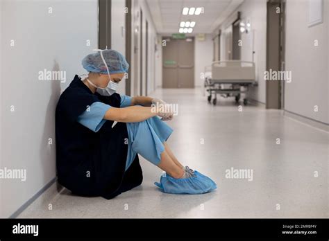Tired Caucasian Female Doctor Wearing Hair Net And Face Mask Sitting In