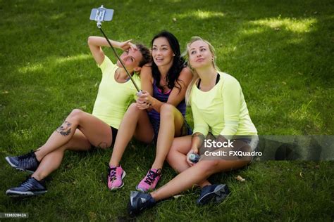 야외 공원에서 잔디에 앉아 세 명의 스포티 한 여성 친구 막대기로 전화에 셀 카를 확인 건강한 생활방식에 대한 스톡 사진 및 기타 이미지 건강한 생활방식 관능 나이