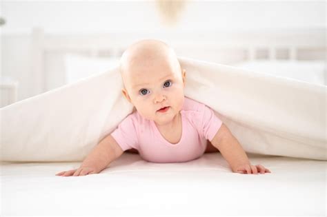 Uma Garotinha Sorridente E Fofa Em Uma Roupa Rosa Está Deitada Na Cama
