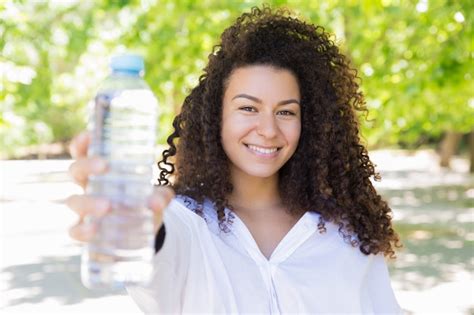Heureuse Jolie Jeune Femme Montrant Une Bouteille D Eau Dans Le Parc