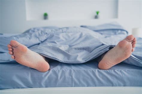 Cropped Photo Of Mature Guy Legs Lying Bed Under Warm Blanket Indoors