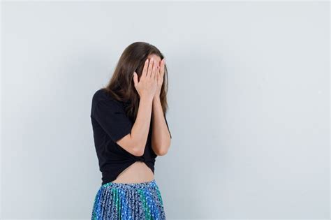 블라우스에 젊은 아가씨 손으로 얼굴을 덮고 무서워 보이는 치마 무료 사진