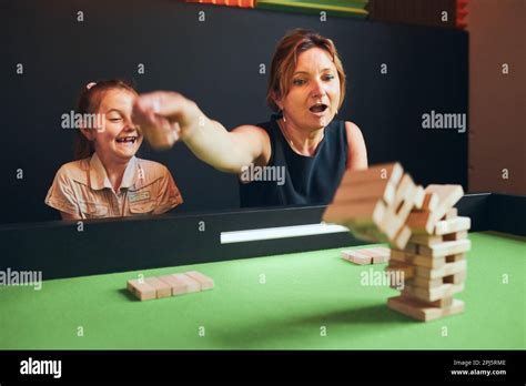 Excited Woman Playing Jenga Game With Her Daughter In Play Room Woman