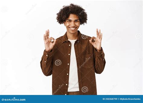 Portrait Of Smiling Hispanic Guy Shows Okay Ok Approval Sign Agree