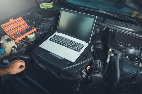 Premium Photo | Professional car mechanic working in auto repair service using laptop on car