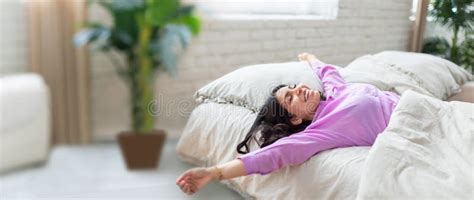Young Woman Enjoying A Morning Stretch In A Bright Cozy Bedroom Stock