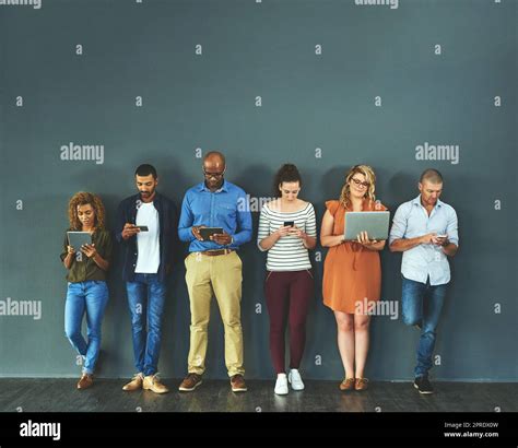 Diverse Group Of People Browsing Social Media On A Phone Tablet And Laptop In Studio On A Grey