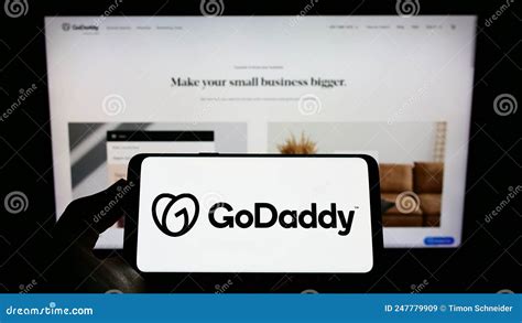 Person Holding Smartphone With Logo Of Us Web Hosting Company Godaddy