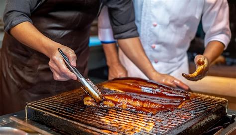 Apprentice Chef Learning To Grill Unagi Eel Over A Charcoal Grill Premium Ai Generated Image