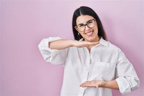 Young Brunette Woman Standing Over Pink Background Gesturing With Hands