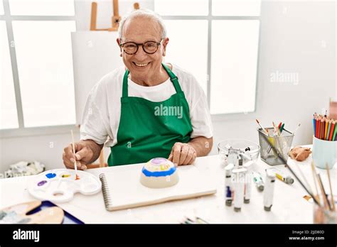 Senior Grey Haired Artist Man Smiling Happy Painting Pottery Sitting On