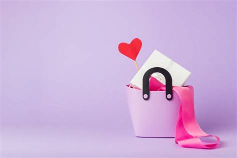 쇼핑 선물 상자 막대기에 심장 분홍색 리본 보라색 배경에 대한 작은 비닐 봉투 연말연시 쇼핑 세일 블랙 프라이데이 사이버 먼데이 발렌타인 데이의 컨셉 12월에 대한 스톡