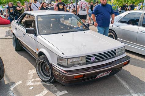 A White Hatchback Car With Aftermarket Modifications Is Parked On A