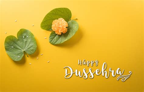 행복한 Dussehra 노란 꽃 녹색 잎 쌀 그리고 노란 종이 배경에 있는 텍스트 두세라 인디언 축제 개념입니다 Dussehra