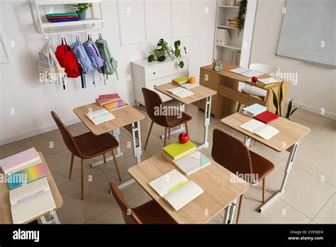 Interior Of Empty Classroom With School Desks And Backpacks Hanging On