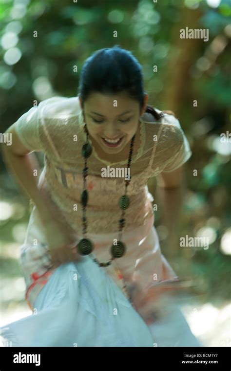Young Woman Bending Over Outdoors Holding Up Skirt Smiling Stock
