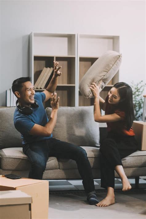 Young Happy Attractive Asian Couple Teasing Each Other With Pillow