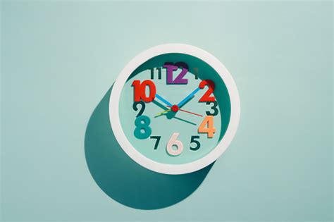 그늘이 있는 파란색 배경에 여러 가지 색상의 숫자가 있는 둥근 어린이 벽 시계 의 사진 위에서 보기 벽 시계에 대한 스톡 사진