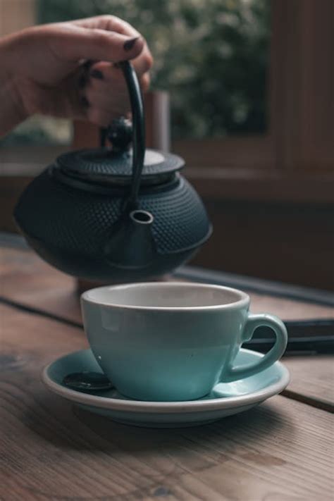 컵 위에 찻주전자를 든 여자 손 · 무료 스톡 사진