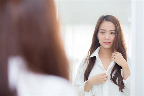 สวยงามของภาพหญิงสาวเอเชียตรวจสอบด้วยใบหน้าและรอยยิ้มมองบนกระจกที่ห้อง