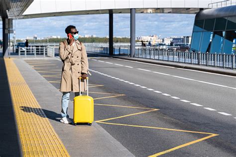 아프로 여행자 남자는 공항 터미널에 서서 모바일과 대기 택시를 호출하고 얼굴 마스크를 착용합니다 25 29세에 대한 스톡 사진