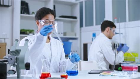Female Chemist Mixing Substances In Lab Typing Experiment Report On Laptop Stock Video
