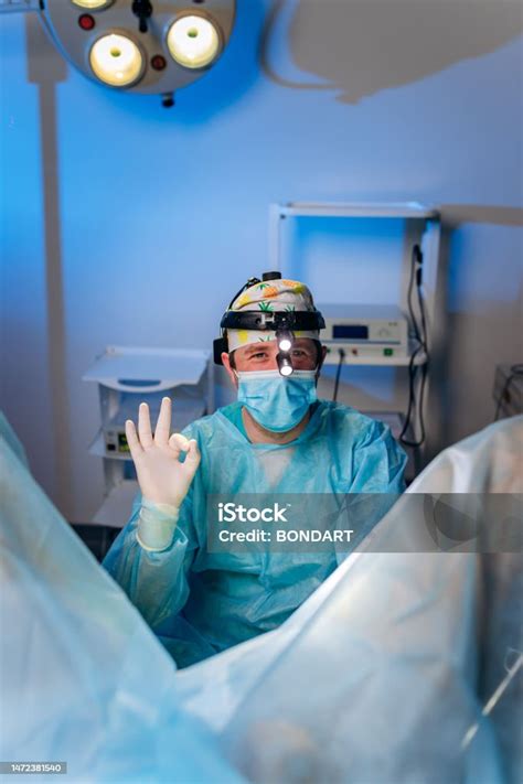 전문 남성 외과 의사 항문 전문의는 병원의 수술실에서 특수 의료 기기를 사용하여 수술을 수행하고 확인 표시를 보여줍니다 긴급