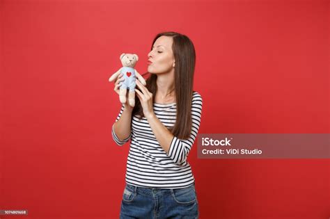 불고 부드러운 젊은 여자의 초상화 키스 하 고 손에 밝은 빨간 벽 배경에 고립 된 테 디 베어 봉 제 장난감 공기 키스 보내기 사람들이 진심으 감정 라이프 스타일 개념 복사