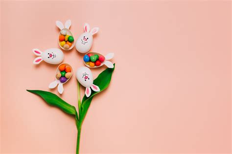 사탕 초콜릿 달걀로 가득 토끼 귀와 재미 계란 용기로 만든 꽃 모양의 최고 보기 부활절 핑크 베이지 색 배경 토끼 토끼 기호