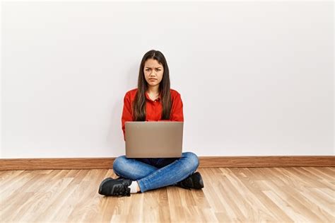 노트북 회의와 긴장 교차 팔로 얼굴에 표정을 거부와 빈 방에 바닥에 앉아 젊은 갈색 머리 여자 부정적인 사람 20 24세에 대한