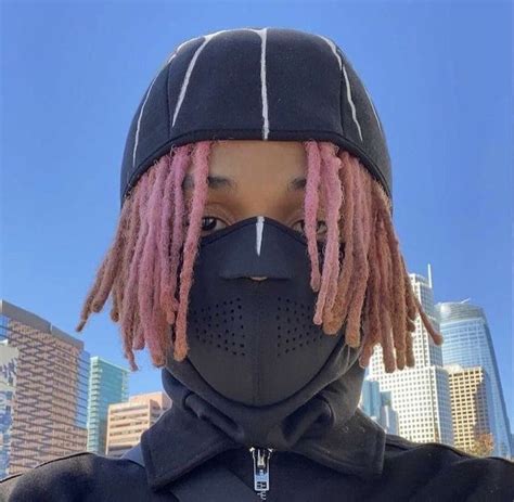 A Man With Pink Dreadlocks Wearing A Black Mask And Jacket In Front Of