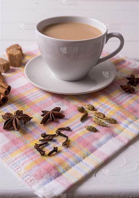 马萨拉奶茶在一个大杯子红糖肉桂棒和茴芹在白色的桌子背景