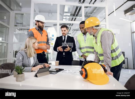Multi Ethnic Partners Discussing Construction Project At Modern Office