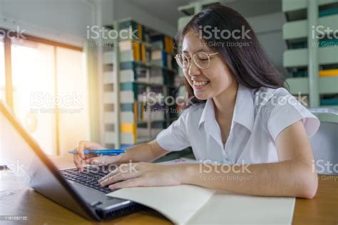 아시아 대학 학생 소녀 독서 책과 노트북 및 스마트 휴대 전화와 함께 작업을 수행 하는 그녀의 숙제에서 공공 도서관에서 교실에