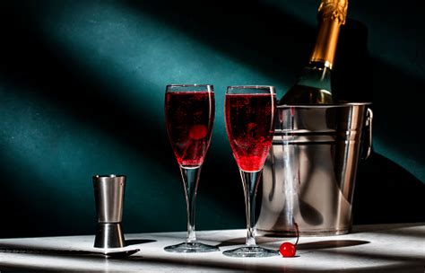 검은 건포도 리큐어 프로 세코 와인 및 레드 칵테일 체리를 곁들인 Kir Royale 칵테일 짙은 녹색 배경 단단한 빛과 그림자