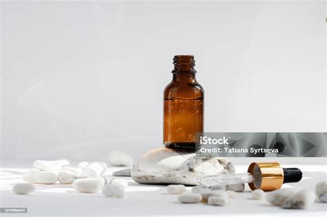 단단한 그림자와 돌이 있는 흰색 회색 배경에 있는 돌 연단에 열린 유리 드롭퍼 병을 모으세요 하드 섀도우 흰색 배경에 화장품