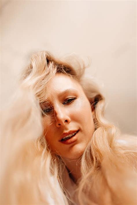 An Attractive Blonde In A White Shirt Looks Down Into The Camera Stock