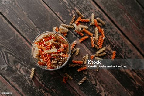 부엌에서 스마트 식품 저장 옵션 생 파스타와 주위에 흩어져 있는 오렌지 나선형 파스타를 저장하기위한 유리 항아리 곡초류에 대한