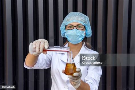 물질로 시험관을 검사하는 화학자 그녀는 회색 추상 회색 배경 위에 보호 유니폼을 입고있어 Stem 주제에 대한 스톡 사진 및