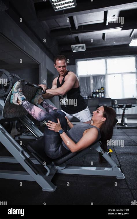 Vertical Shot Of A Professional Personal Trainer Assisting His Female