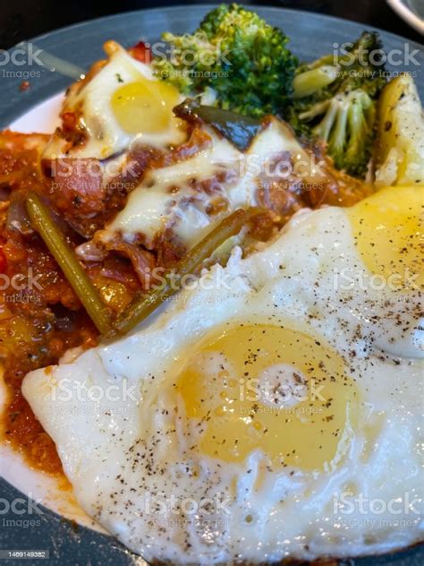 토마토 고추 양파 올리브 오일 마늘 소스에 계란 후라이를 곁들인 파란색 테두리 접시에 샥쇼카 샤크슈카 착추카의 지중해 건강식