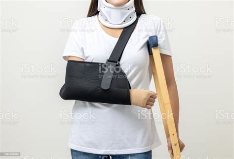 젊은 아시아 여자는 고립 된 팔과 다리를 부러 뜨렸다 여자는 지팡이 목발로 석고 캐스트 부목을 착용했습니다 목 칼라가 있는 슬링