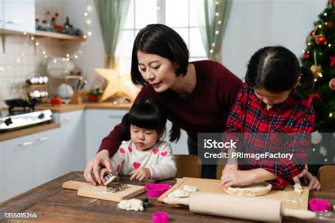 아시아 어머니 도움 그녀의 아기 소녀 사용 A 쿠키 커터 에 이 반죽 을 개척 하는 동안 그들은 집에서 부엌에서 크리스마스 쿠키