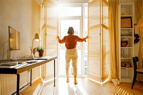La Mujer Abre Las Persianas De La Ventana En La Habitación Soleada