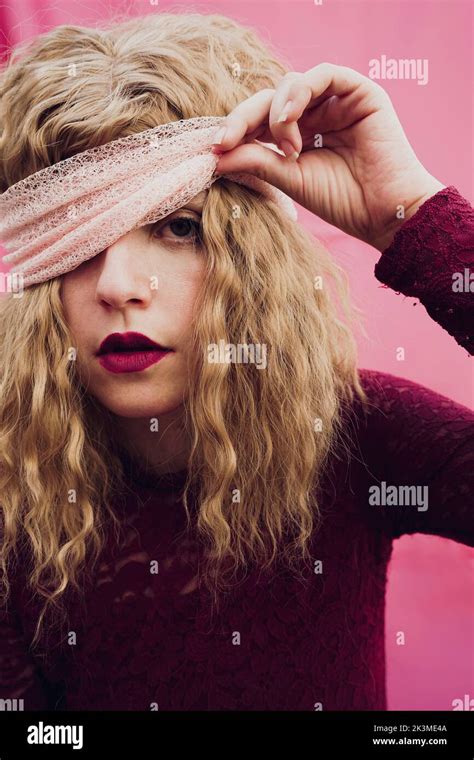 Calm Female Model With Blond Wavy Hair Peeking Out Of Blindfold And